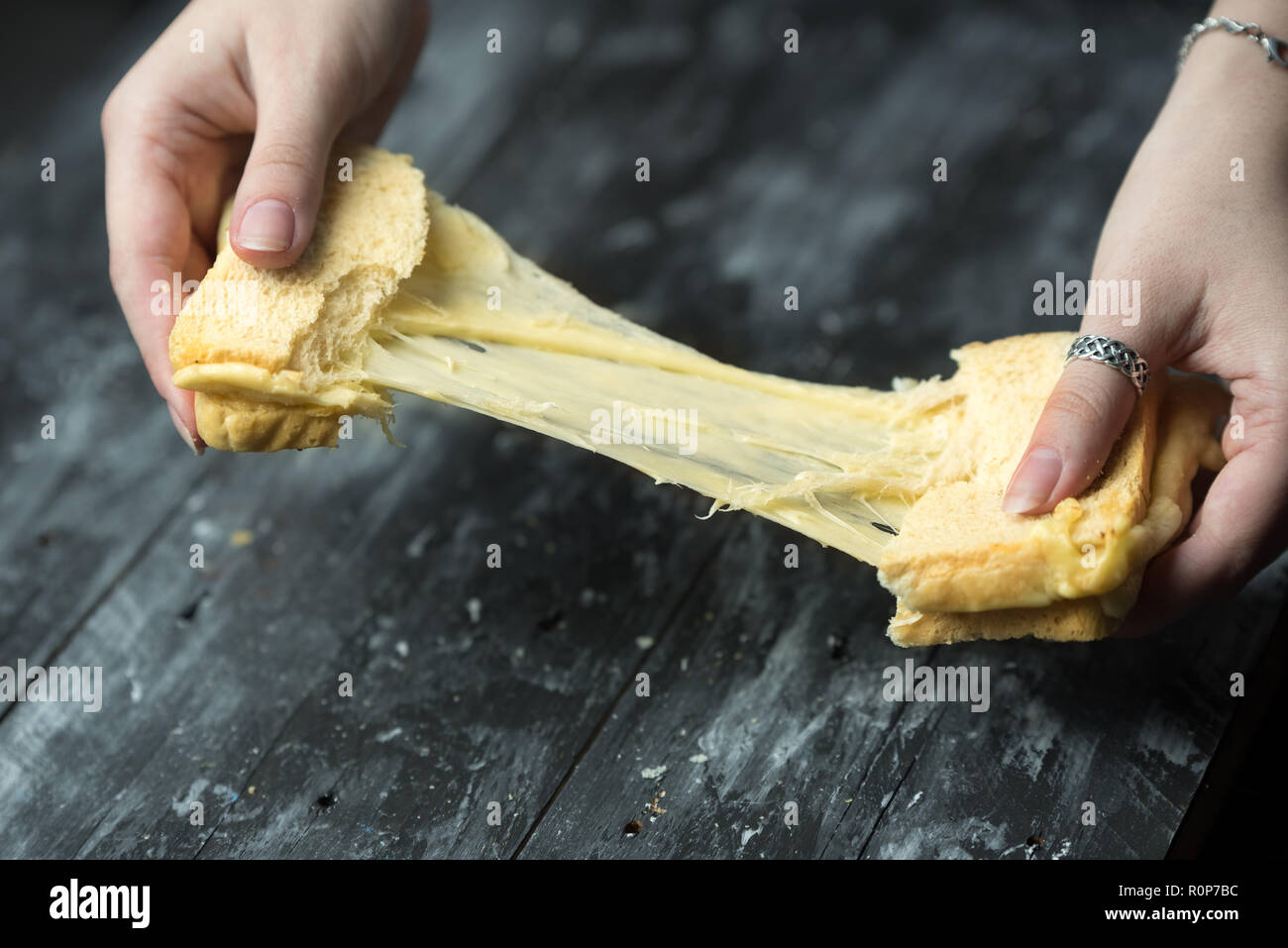 baked toast with stretched cheese in the hands of a woman Stock Photo ...