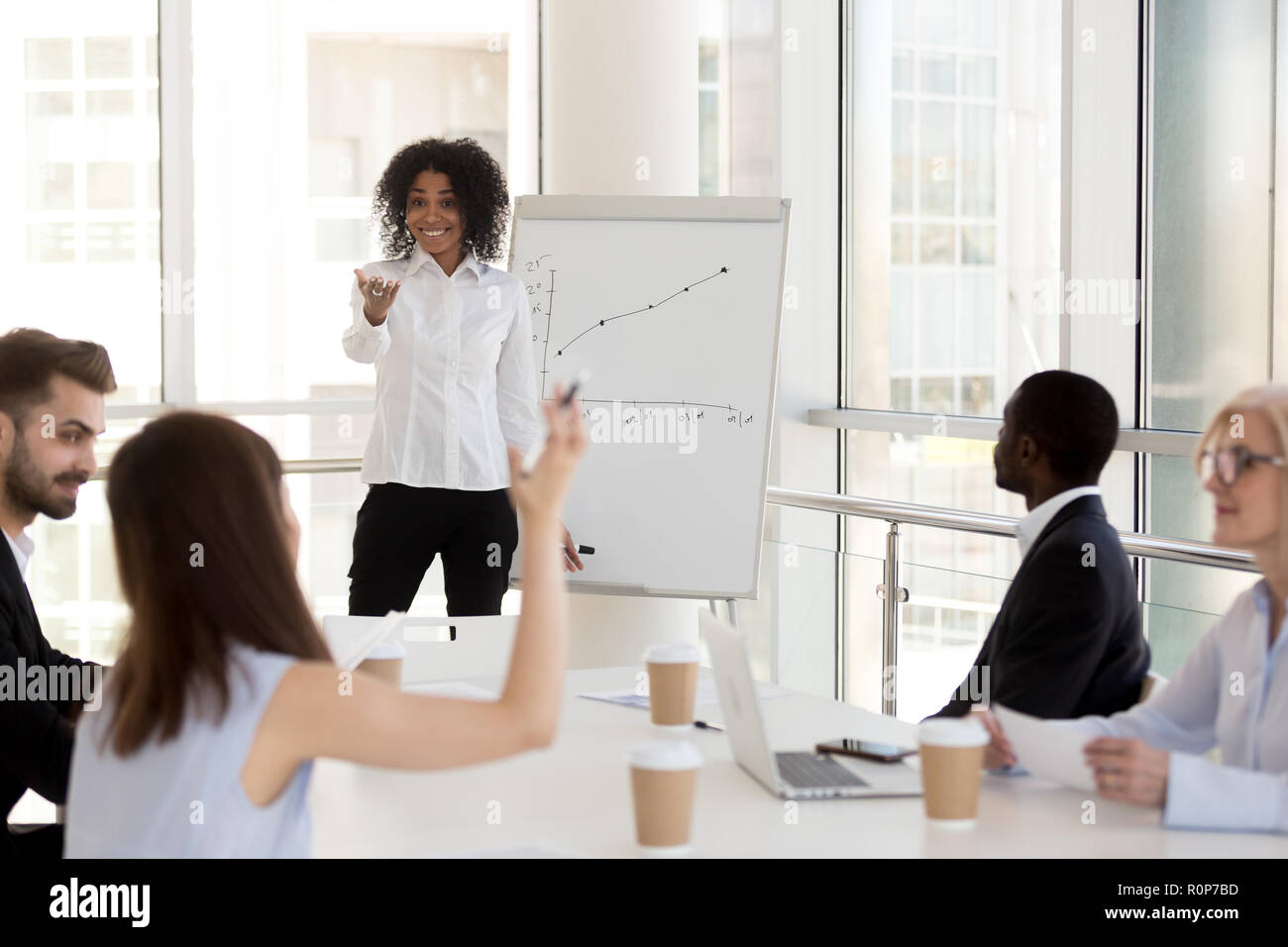 Smiling black female mentor interacting with employees during pr Stock ...