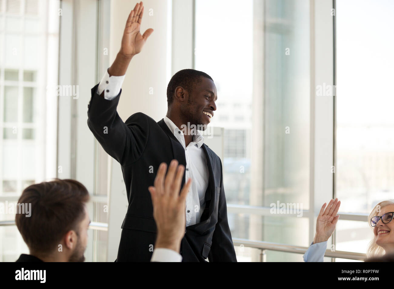 Black male coach hold teambuilding activity with workers raising Stock ...
