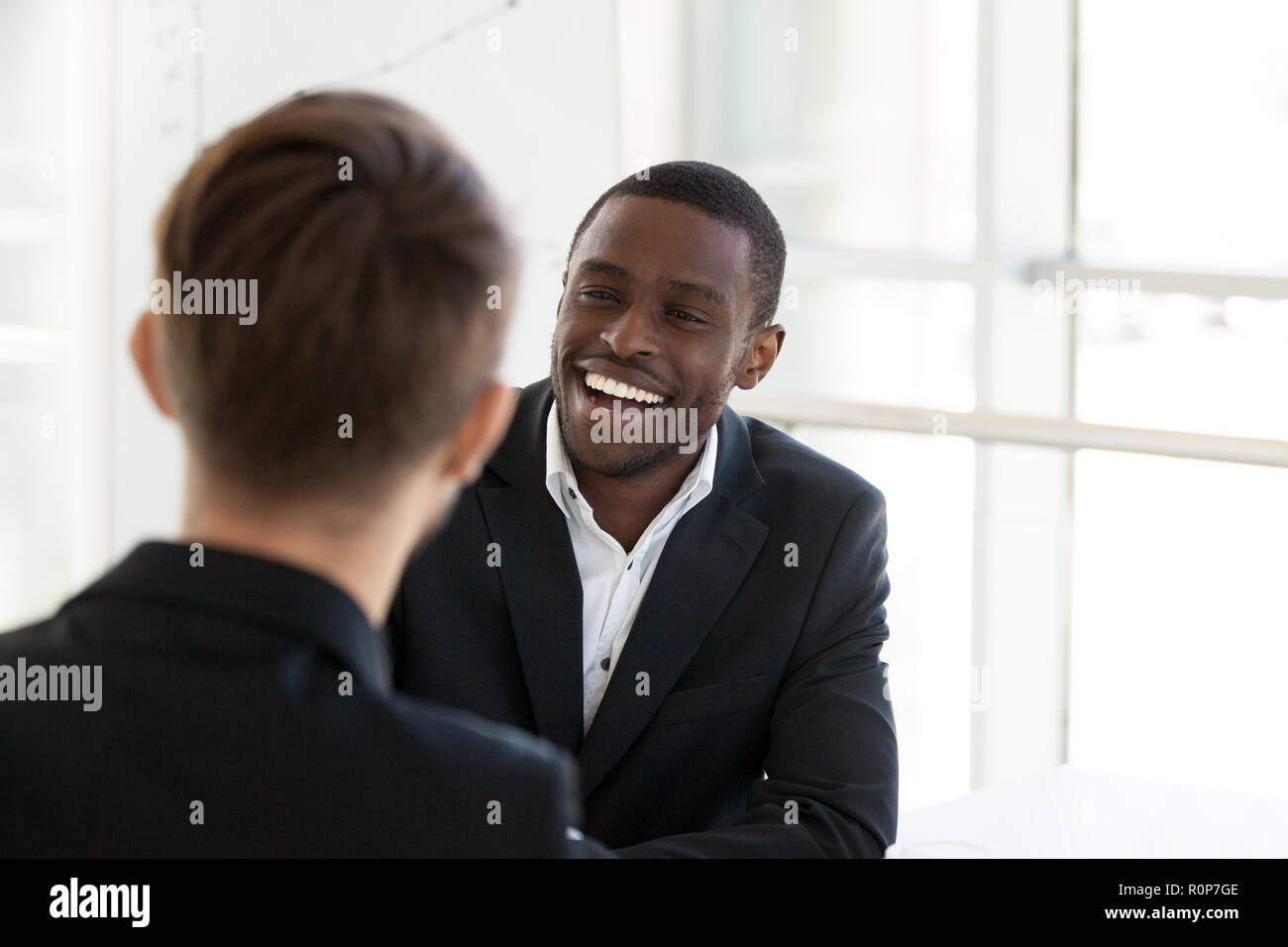 Happy black worker smiling having talk with colleague Stock Photo - Alamy