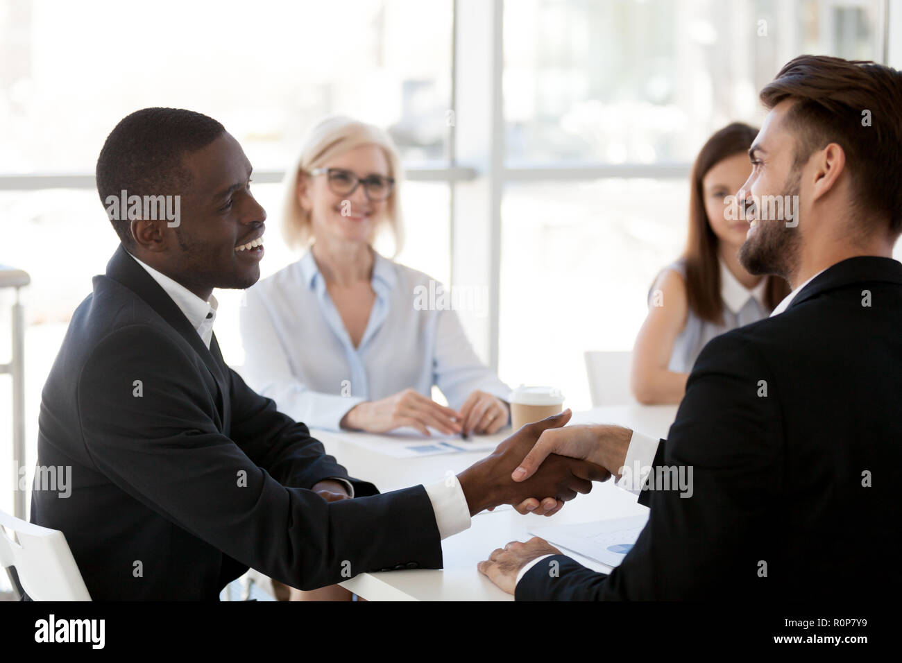 Diverse employees handshake greeting at office meeting Stock Photo - Alamy