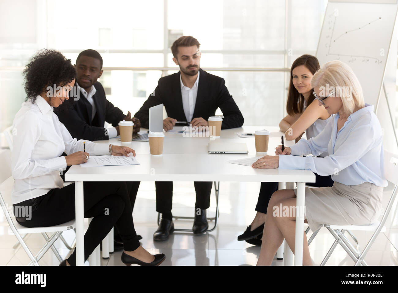 Excited employees watch interns sign contracts at meeting Stock Photo ...