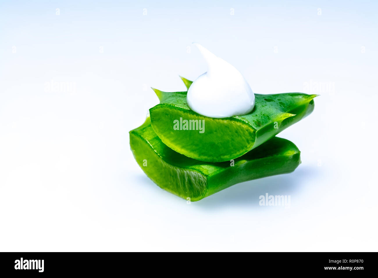 Cut aloe leaf texture close up with a beautiful drop of white cream ...