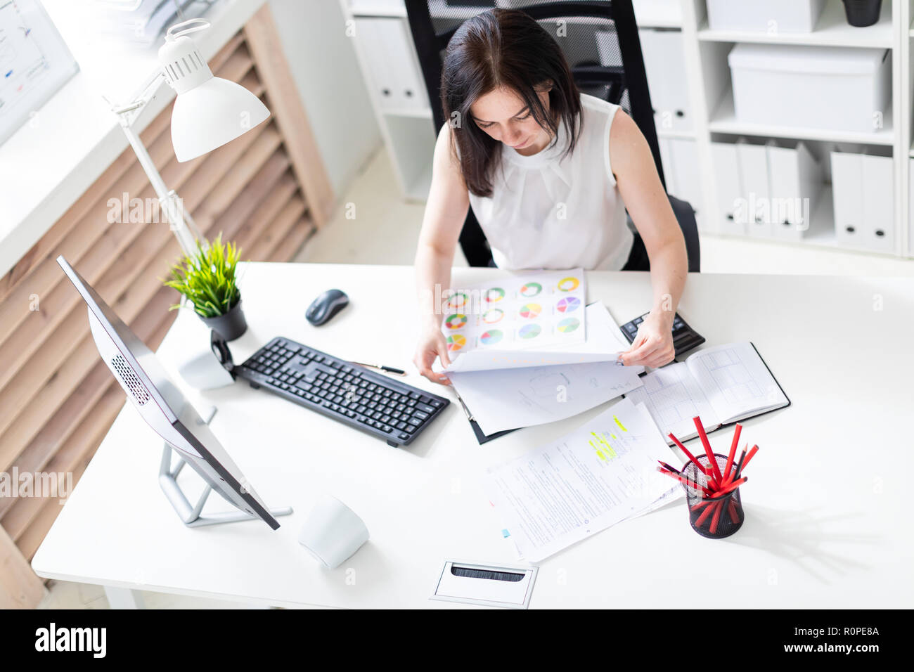 A young girl sitting in the office at a computer Desk and working with ...