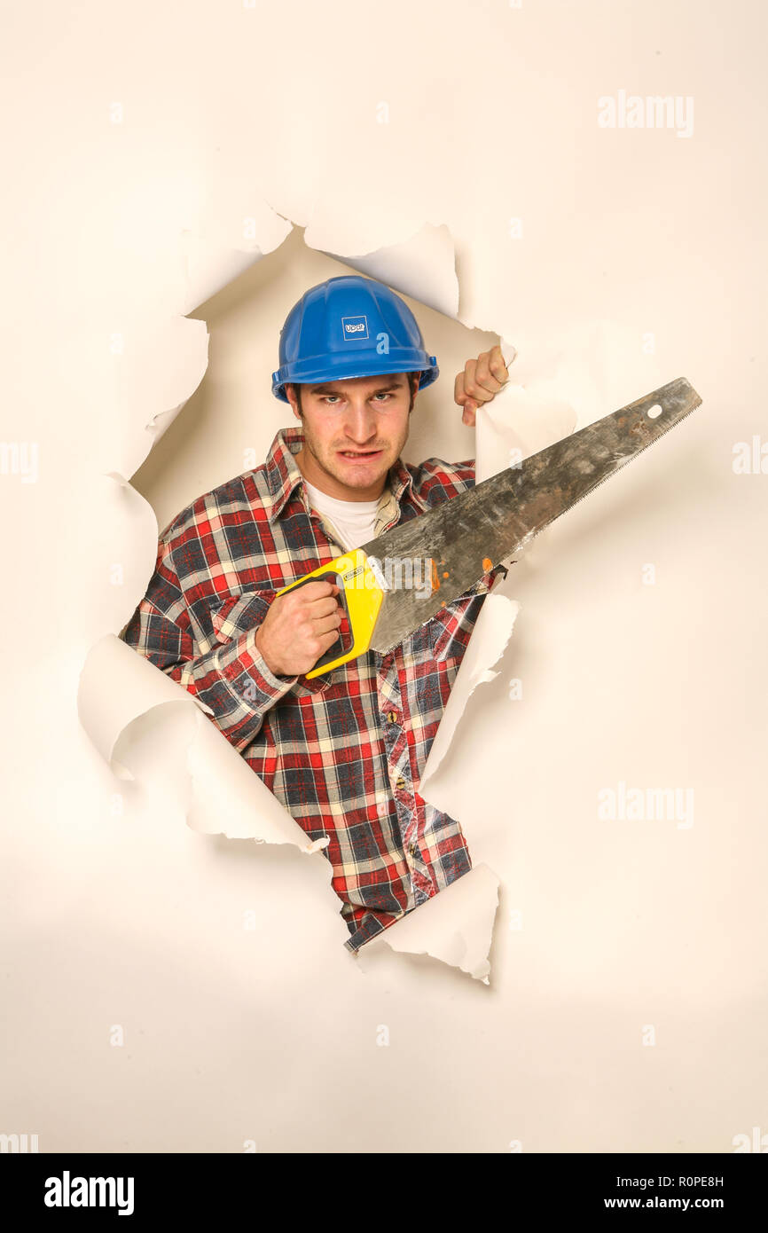 Aggressive handyman busting through a hole in the wall holding a tool ...