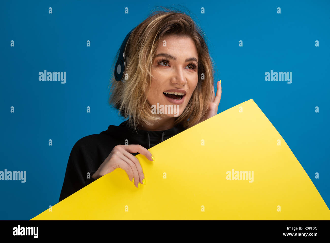 Portrait of woman positively smiling and wearing headphones. Yellow ...