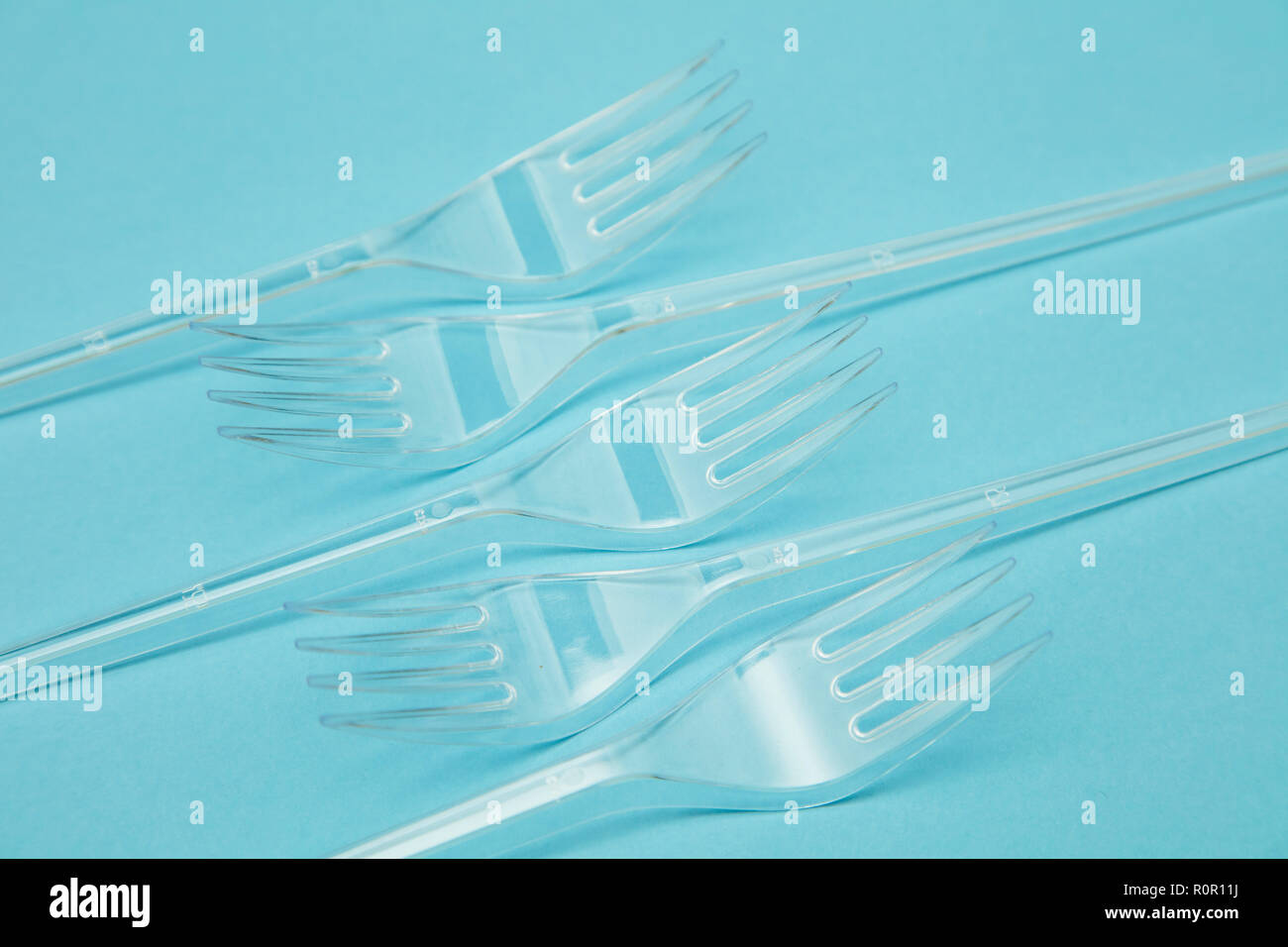 Plastic cutlery forks arranged on a blue background. Plastic waste ...