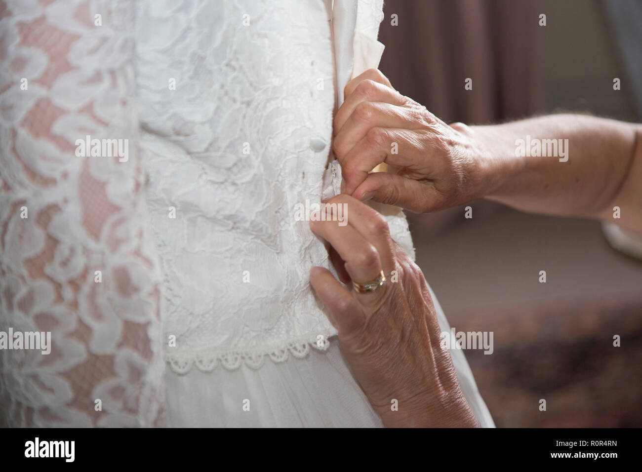 close up of the Bride having her dress done up before she gets married ...