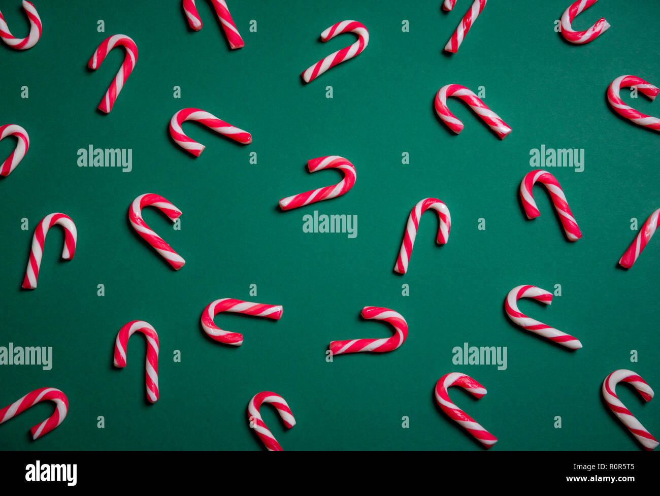 Above view of mini red and white candy canes displayed on a green paper ...
