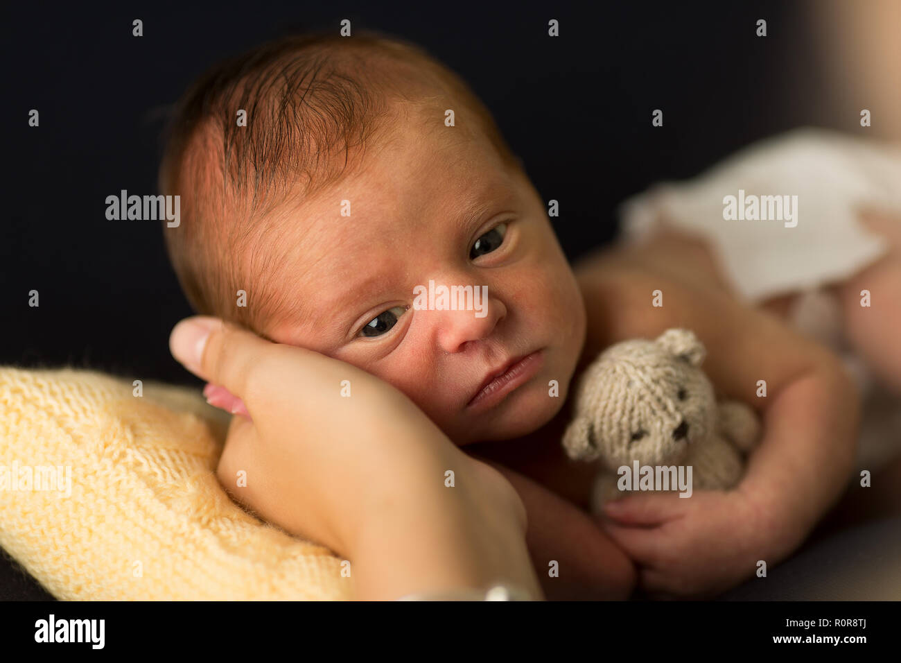 Closeup of charming newborn with toy and mother touching cheek gentle ...