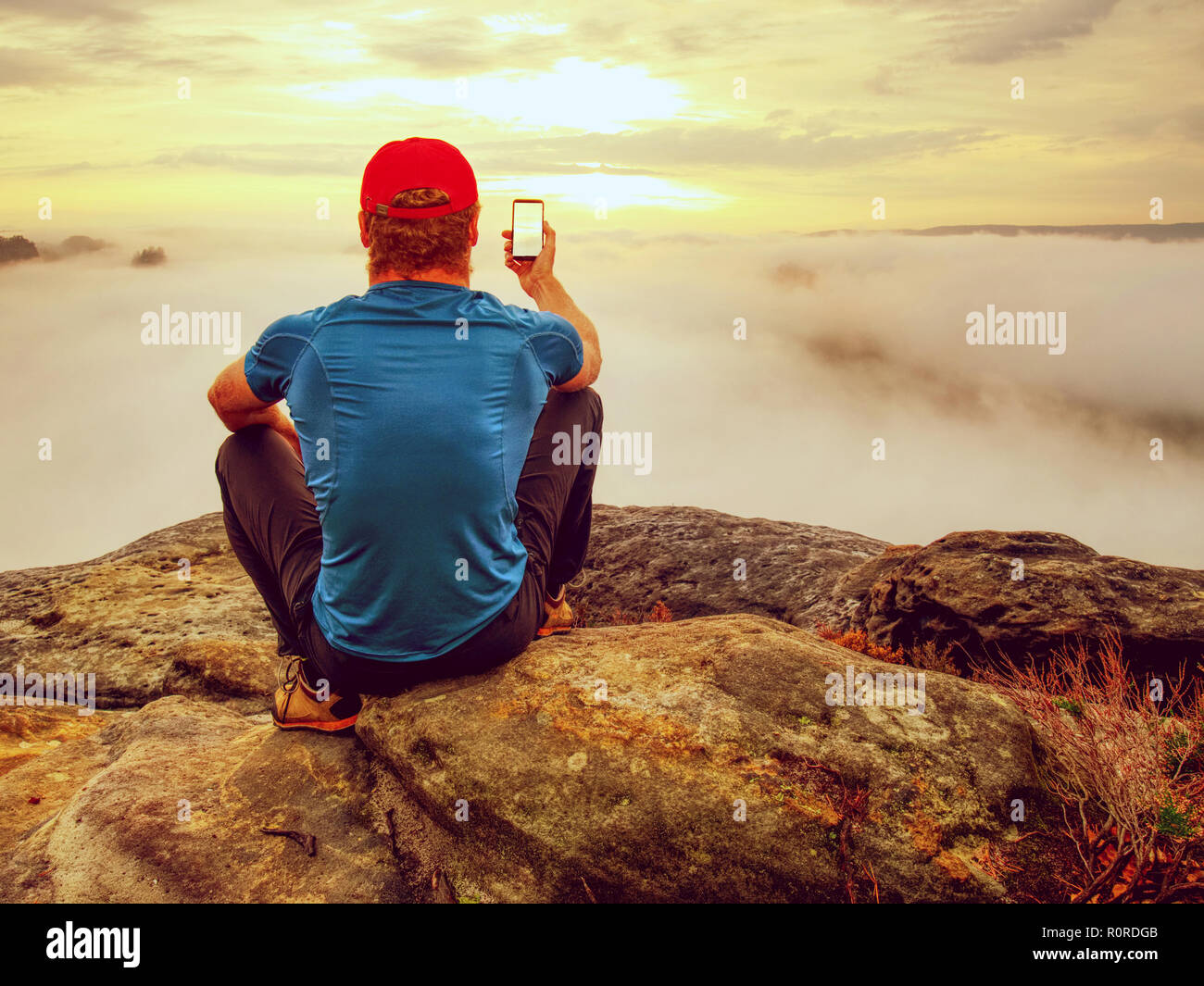Hiker takes selfie photo, fall nature adventure. Man sit on stone on ...