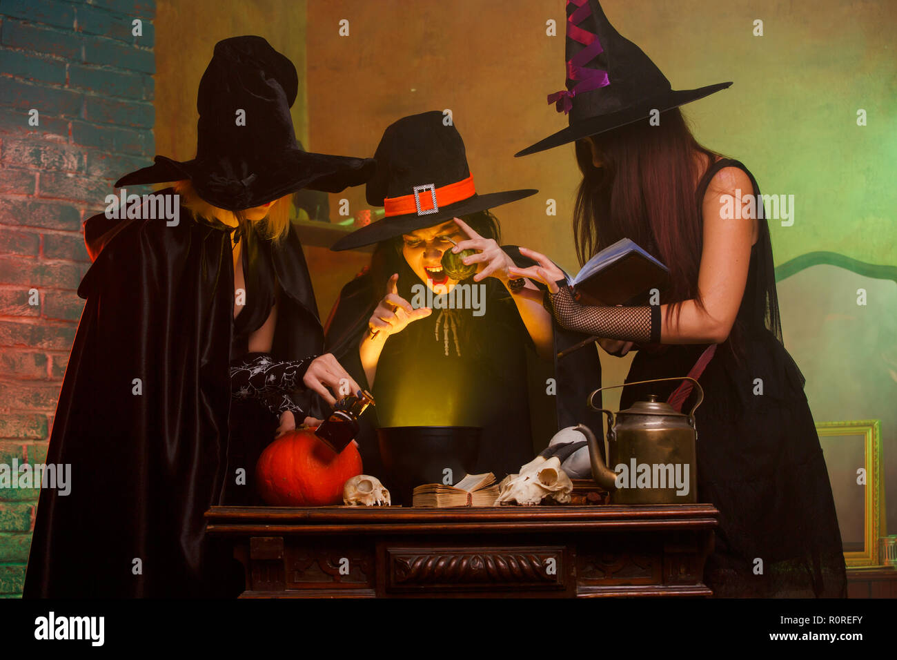 Picture of three witches with book of potions in pot at dark room Stock ...