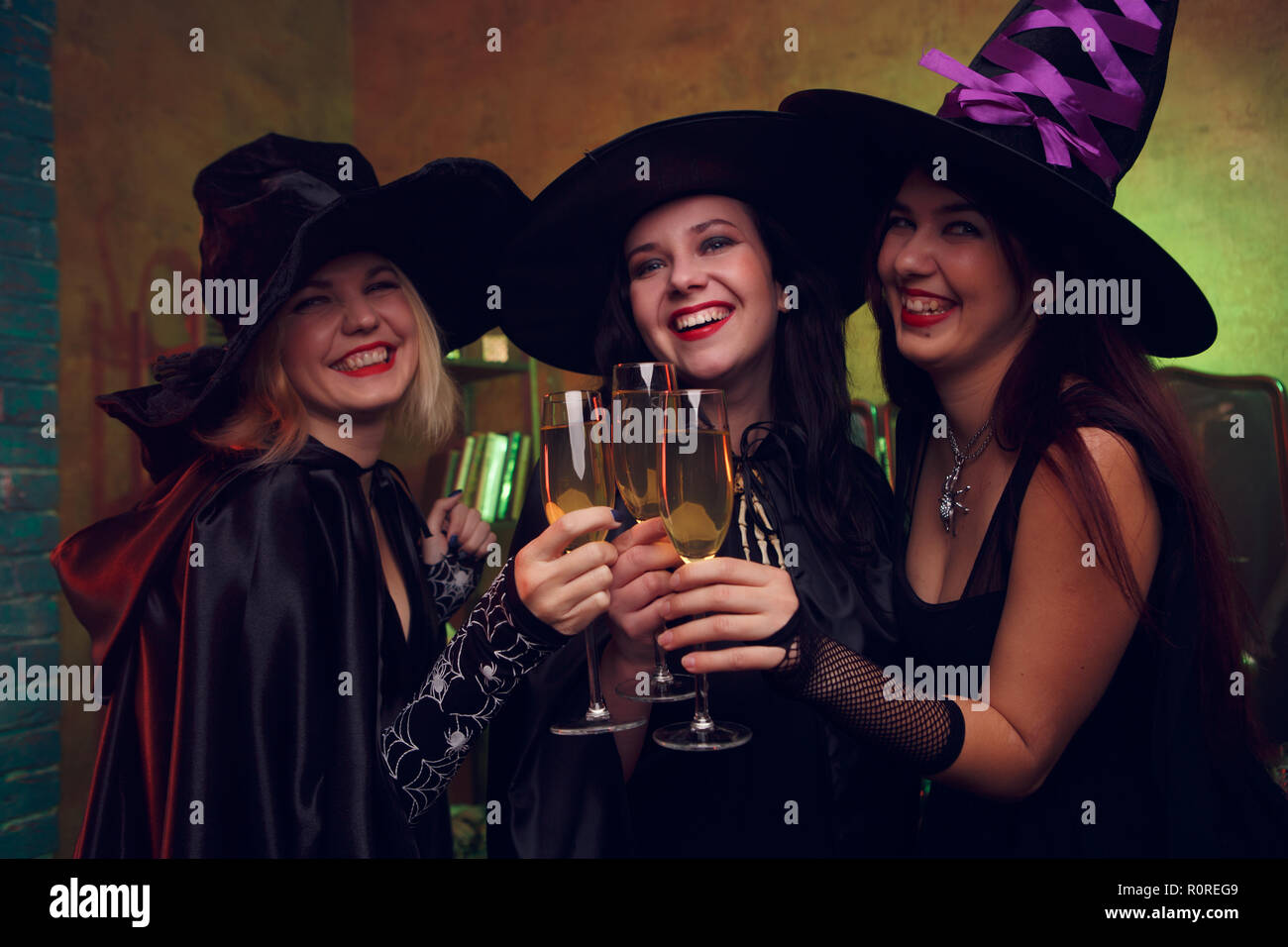 Image of three young witches with glass of champagne at dark room Stock Photo - Alamy