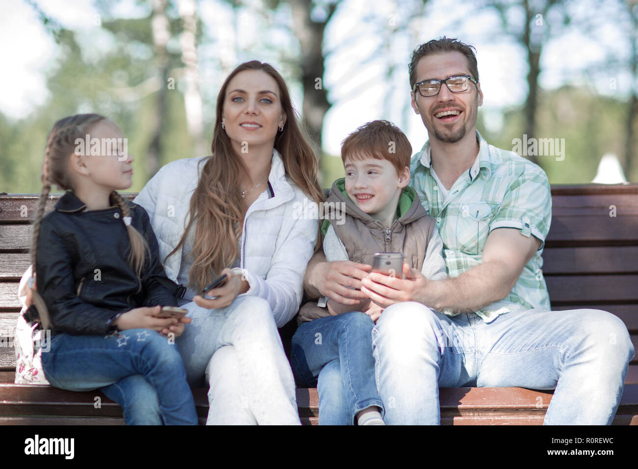 portrait of a happy family sitting on a Park bench Stock Photo - Alamy