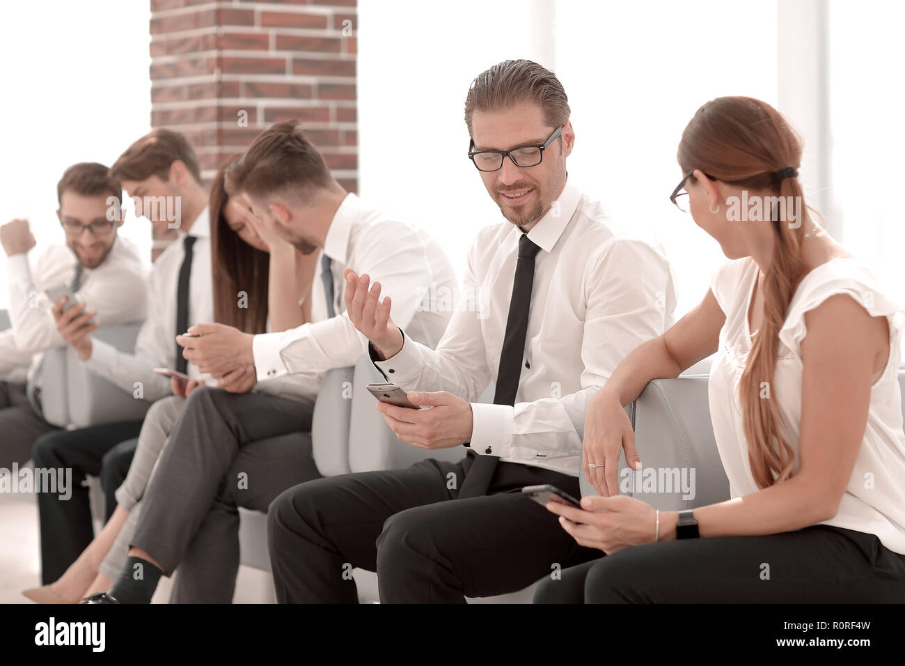 employees of the company using their smartphones sitting in the office ...