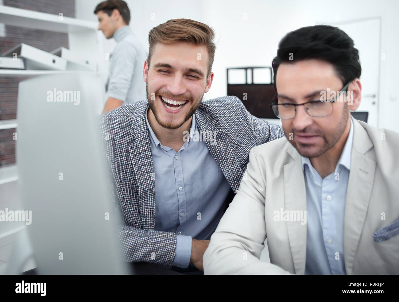 smiling colleagues looking at the computer monitor Stock Photo - Alamy