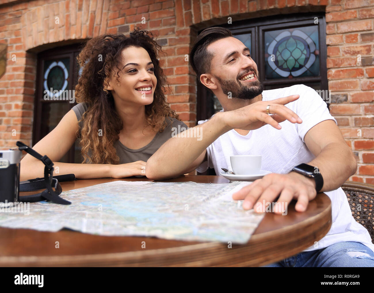 Young tourists drinking coffee at cafe and reading city map Stock Photo ...