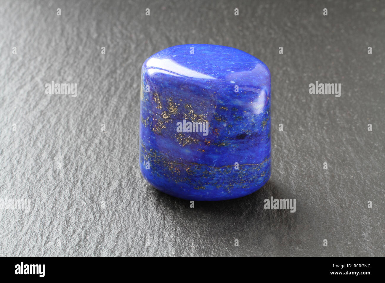 A blue lazurite stone on a black stone board Stock Photo - Alamy
