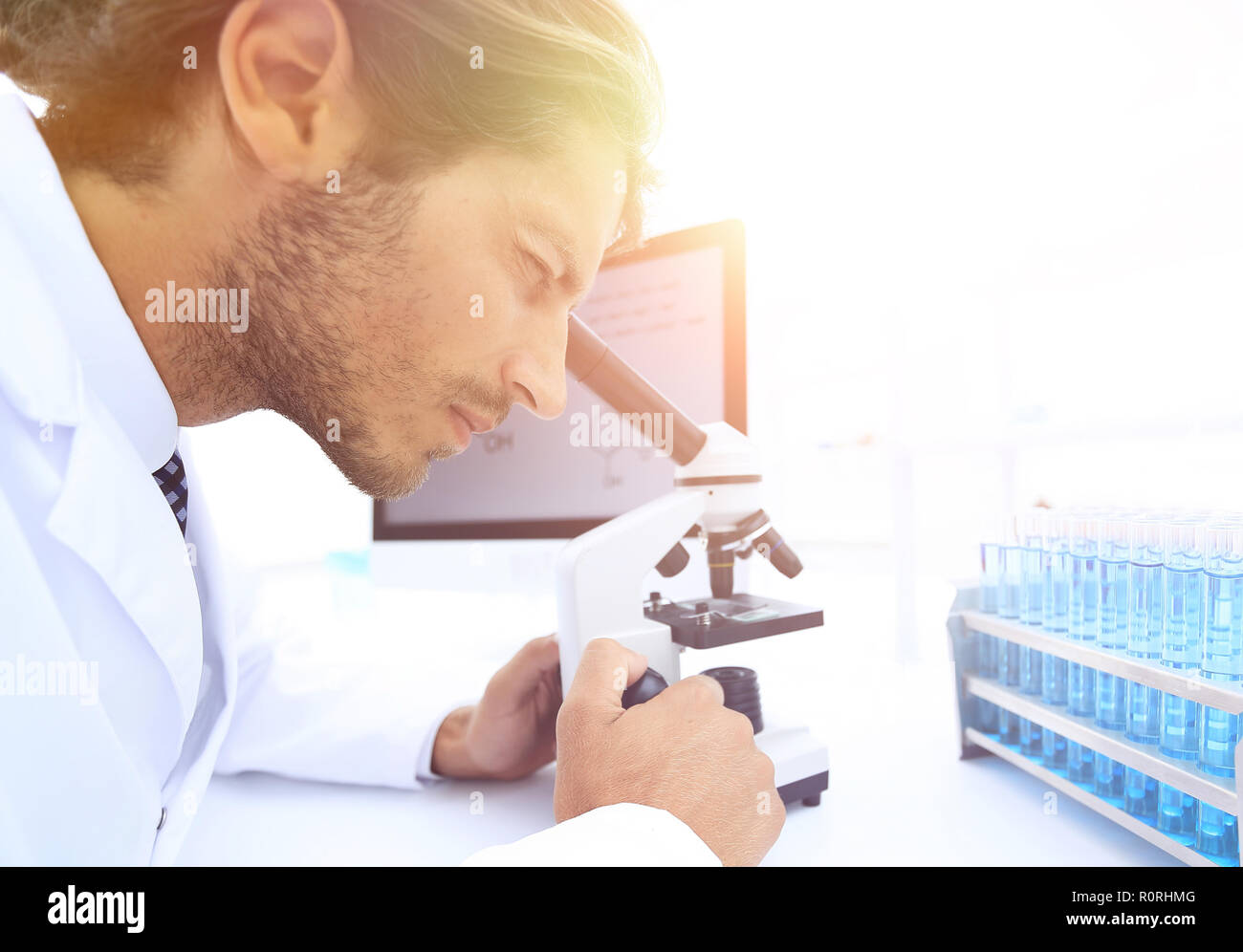 Young laboratory scientist looking at microscope in laboratory Stock ...