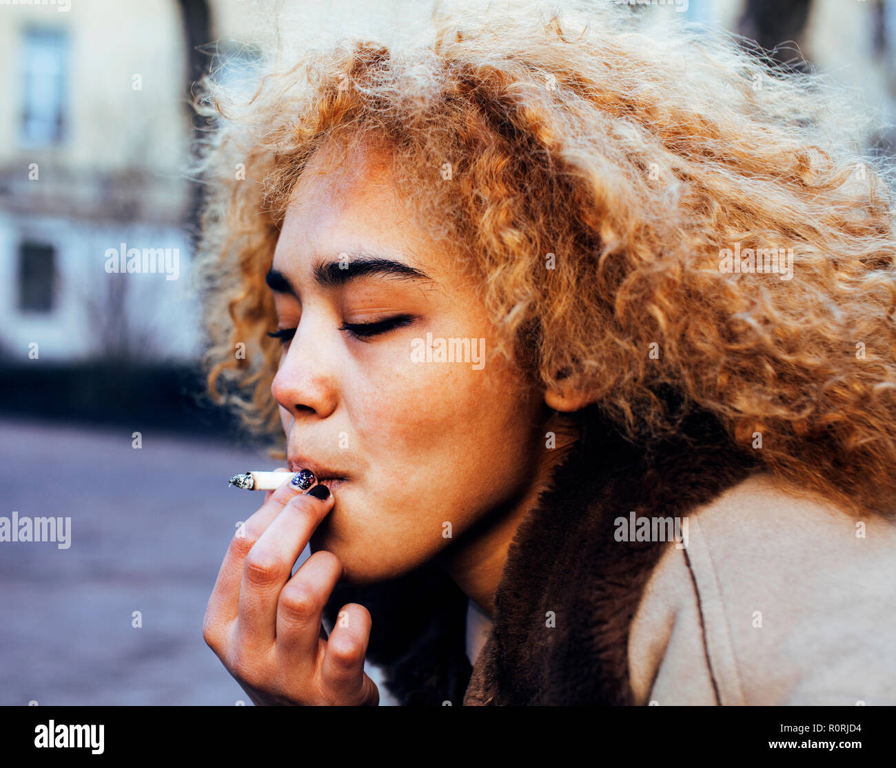 young pretty girl teenage outside smoking cigarette, looking lik Stock Photo - Alamy