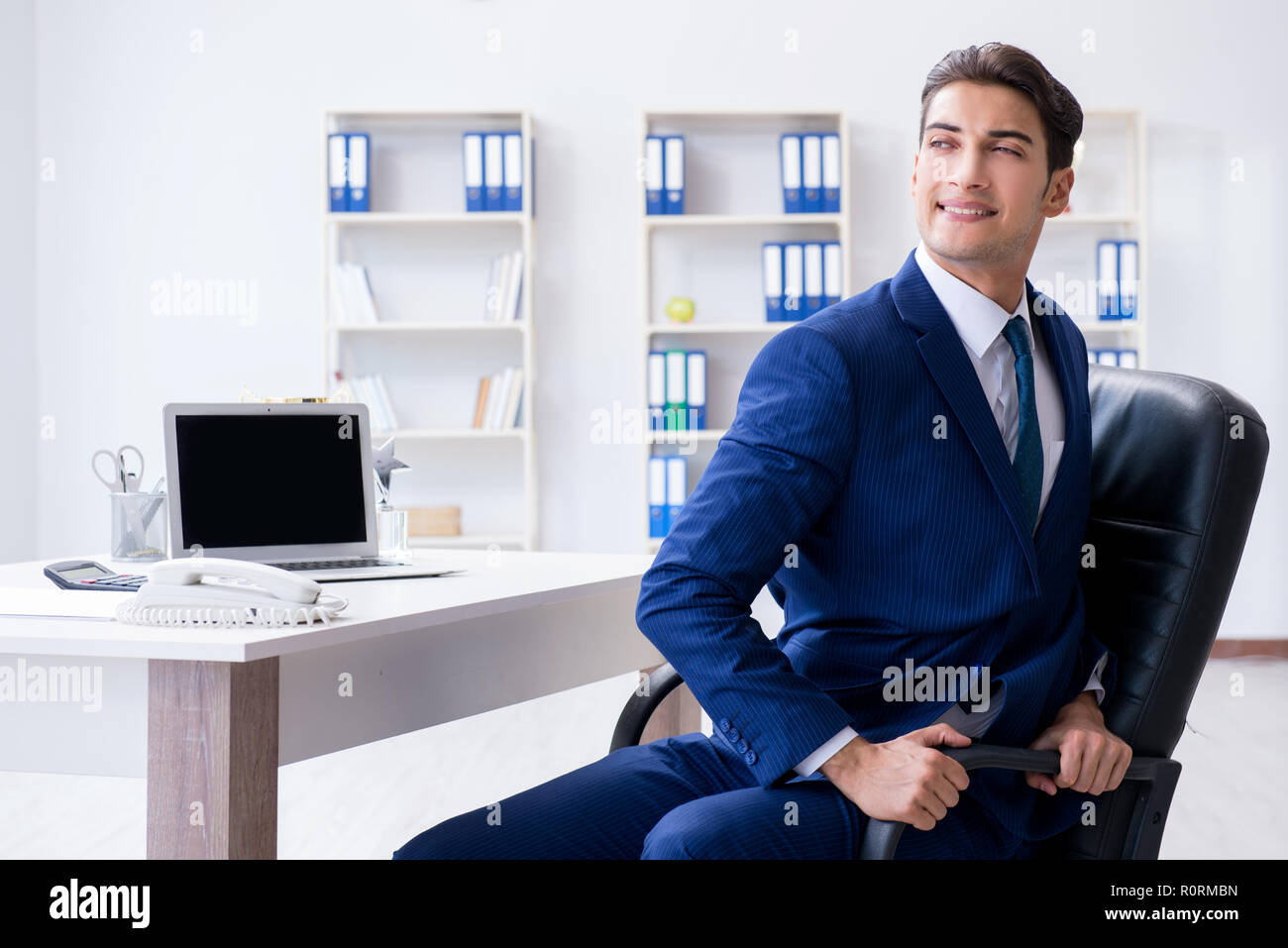 Young businessman doing sports stretching at workplace Stock Photo - Alamy