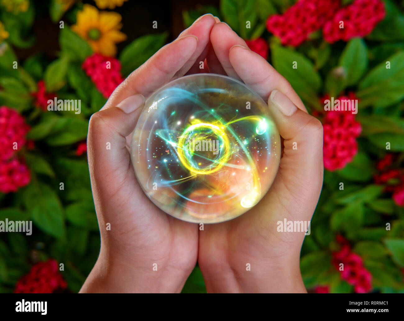 Female hands hold crystal ball atomic particle with flowers in ...