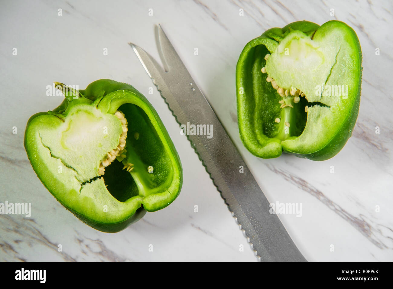 Green bell pepper sliced in half showing seeds and pith Stock Photo - Alamy