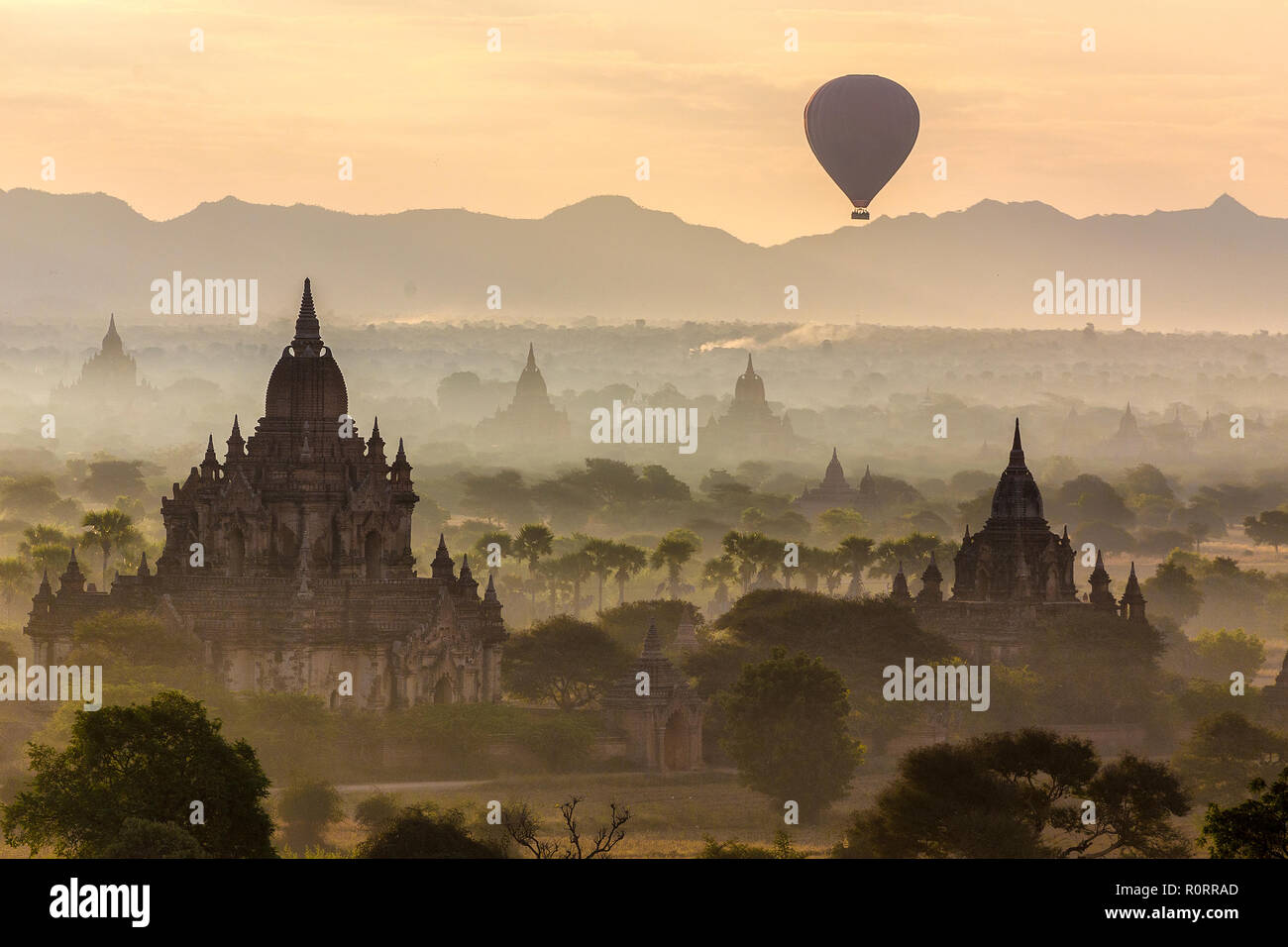 Air balloon flying over pagodas at misty dawn in the plain of Bagan ...