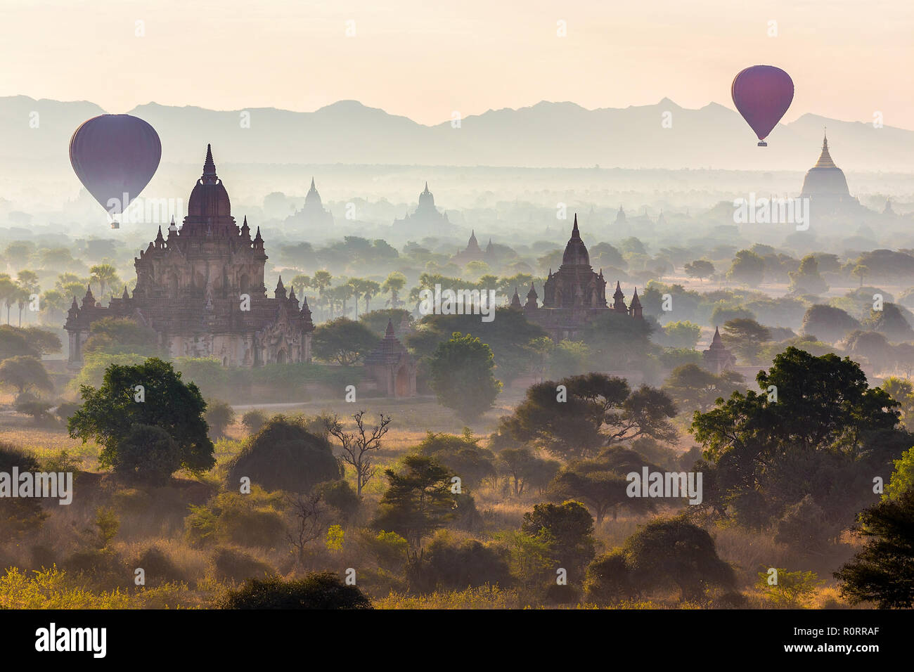 Air balloons flying over pagodas at misty dawn in the plain of Bagan ...