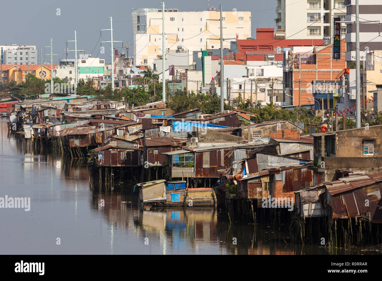 Slum wooden house on the Saigon river bank, in front of modern ...