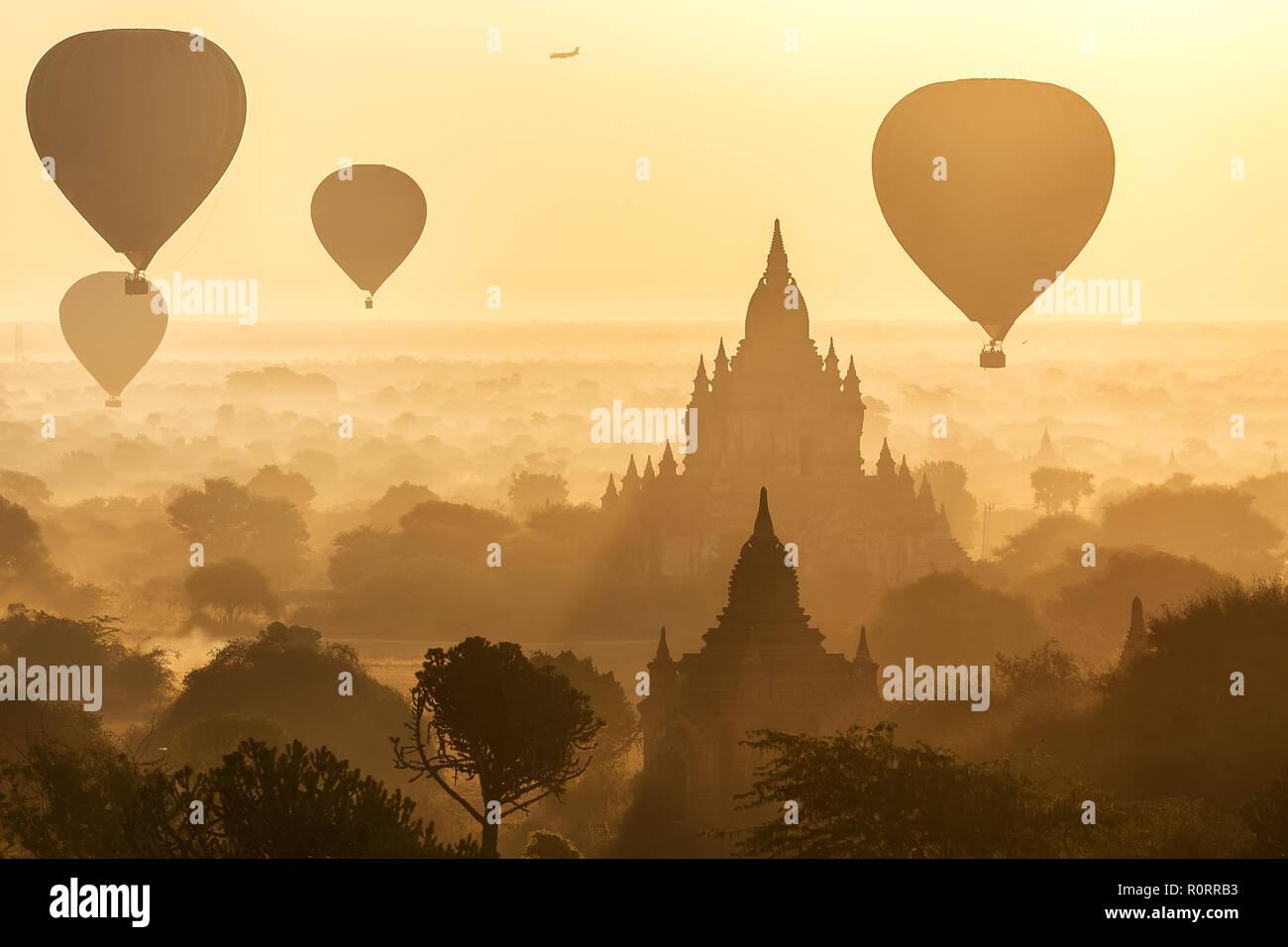 Air balloons flying over pagodas at misty dawn in the plain of Bagan ...