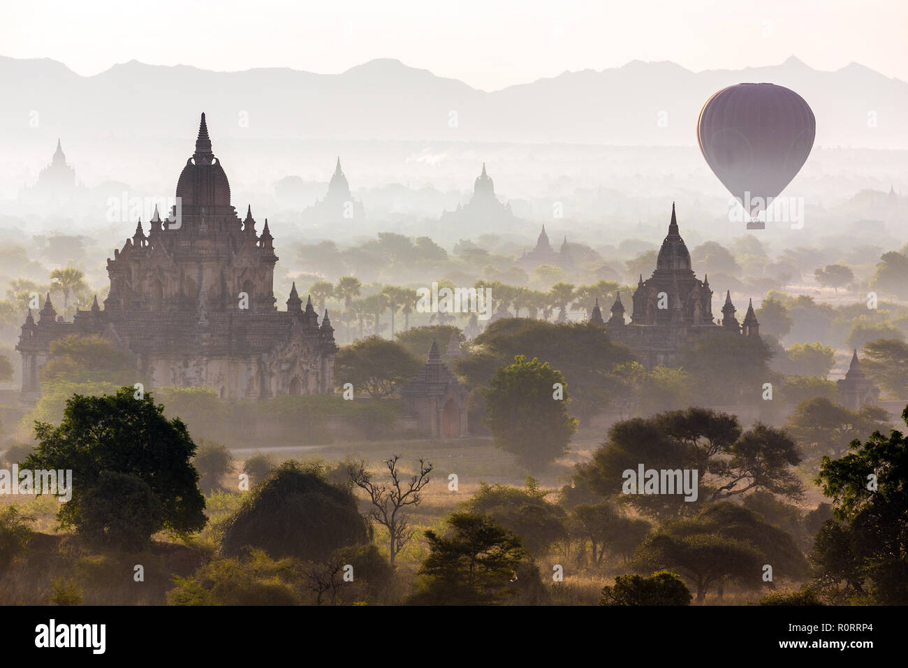 Air balloons flying over pagodas at misty dawn in the plain of Bagan ...