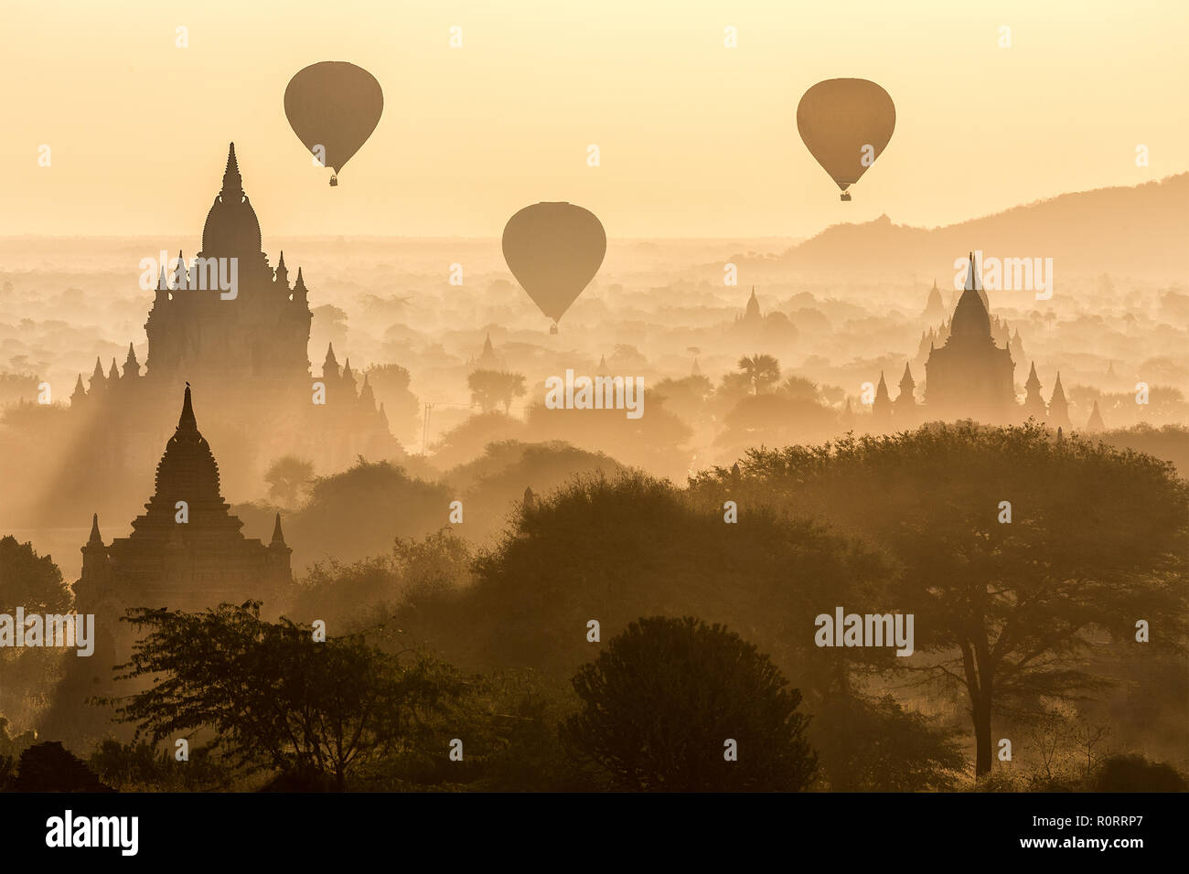 Air balloons flying over pagodas at misty dawn in the plain of Bagan ...