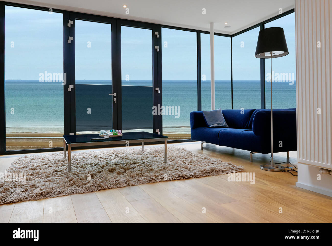 Modern living room with large windows and view on ocean Stock Photo - Alamy