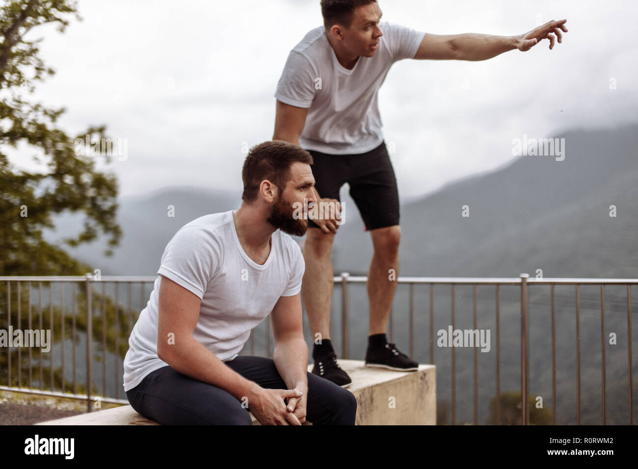 Two athletes rest after intense outdoor workout training in mountain ...