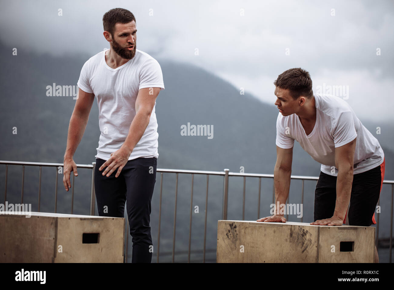 Fit young sportsmen doing box jumps as a group outdoor on top of the ...