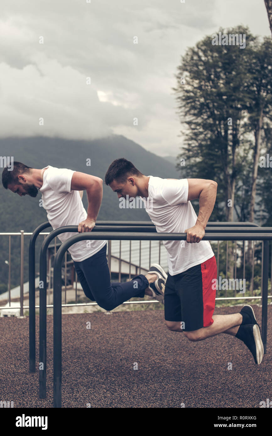 Two sportsmen doing dips on parallel bars Stock Photo - Alamy