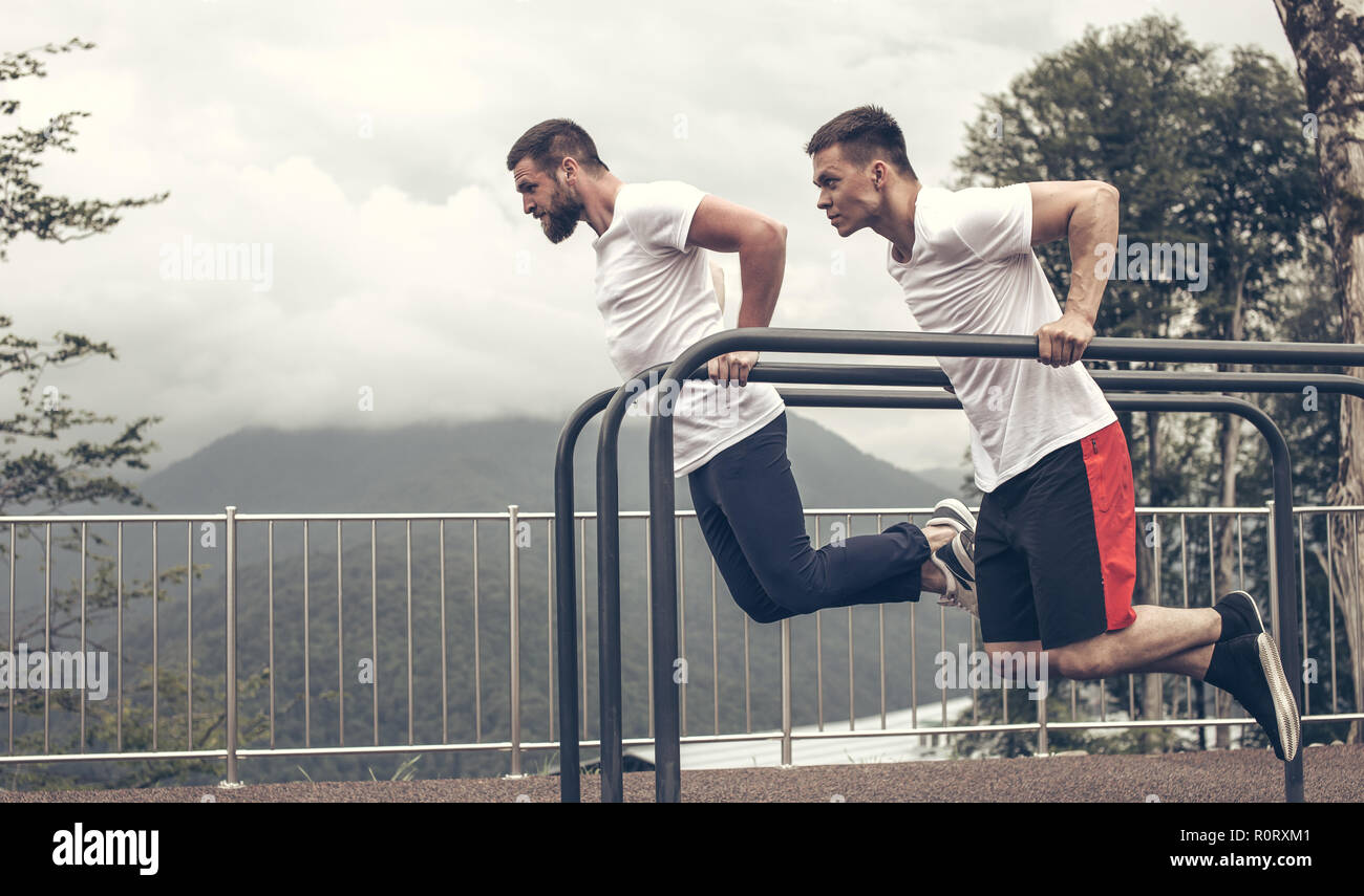 Two sportsmen doing dips on parallel bars Stock Photo - Alamy