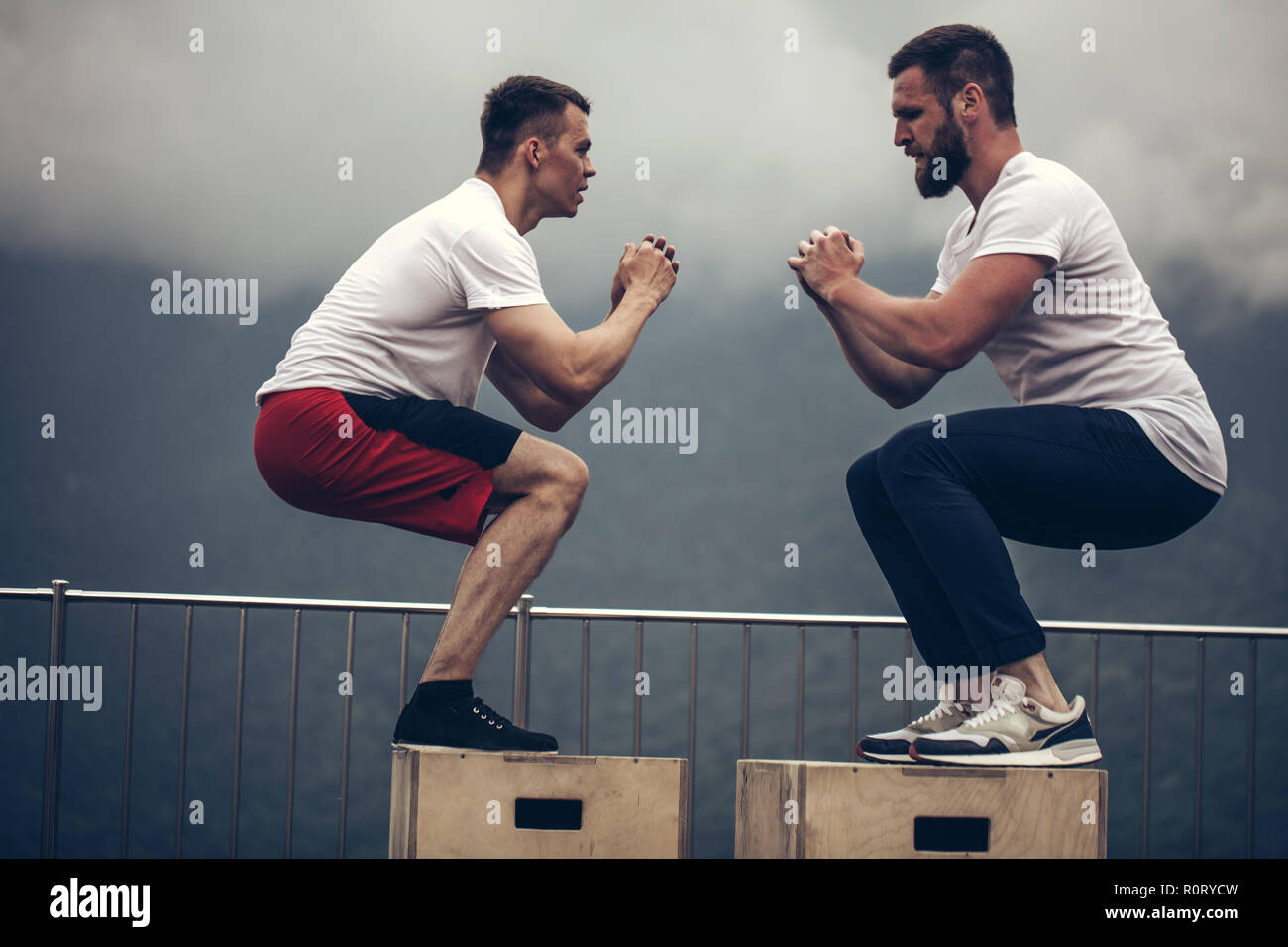 Fit young sportsmen doing box jumps as a group outdoor on top of the ...