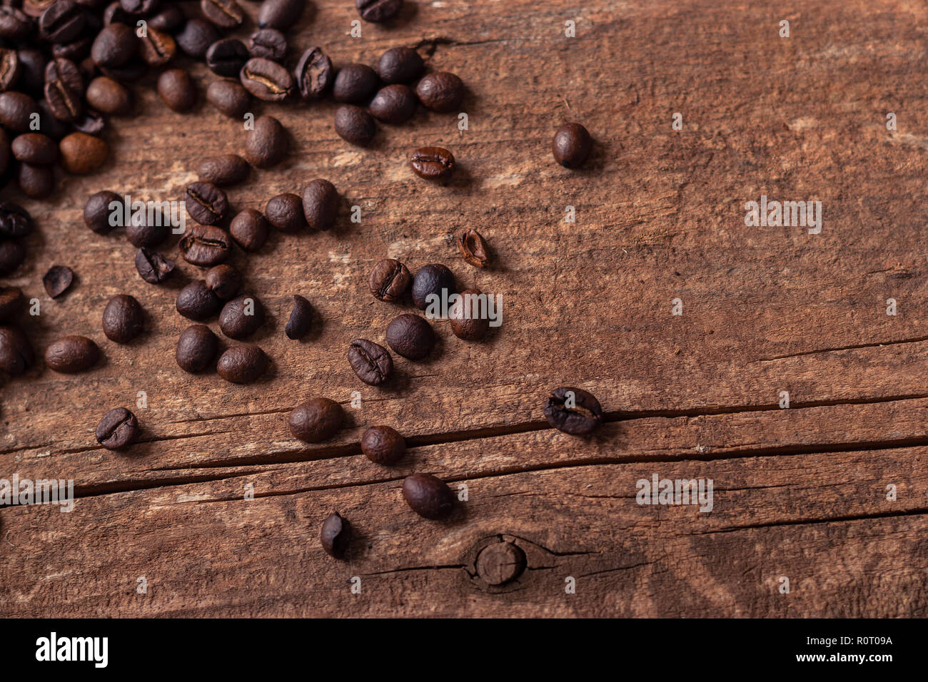 Close-up view of spilled fresh coffee beans on wooden table background ...