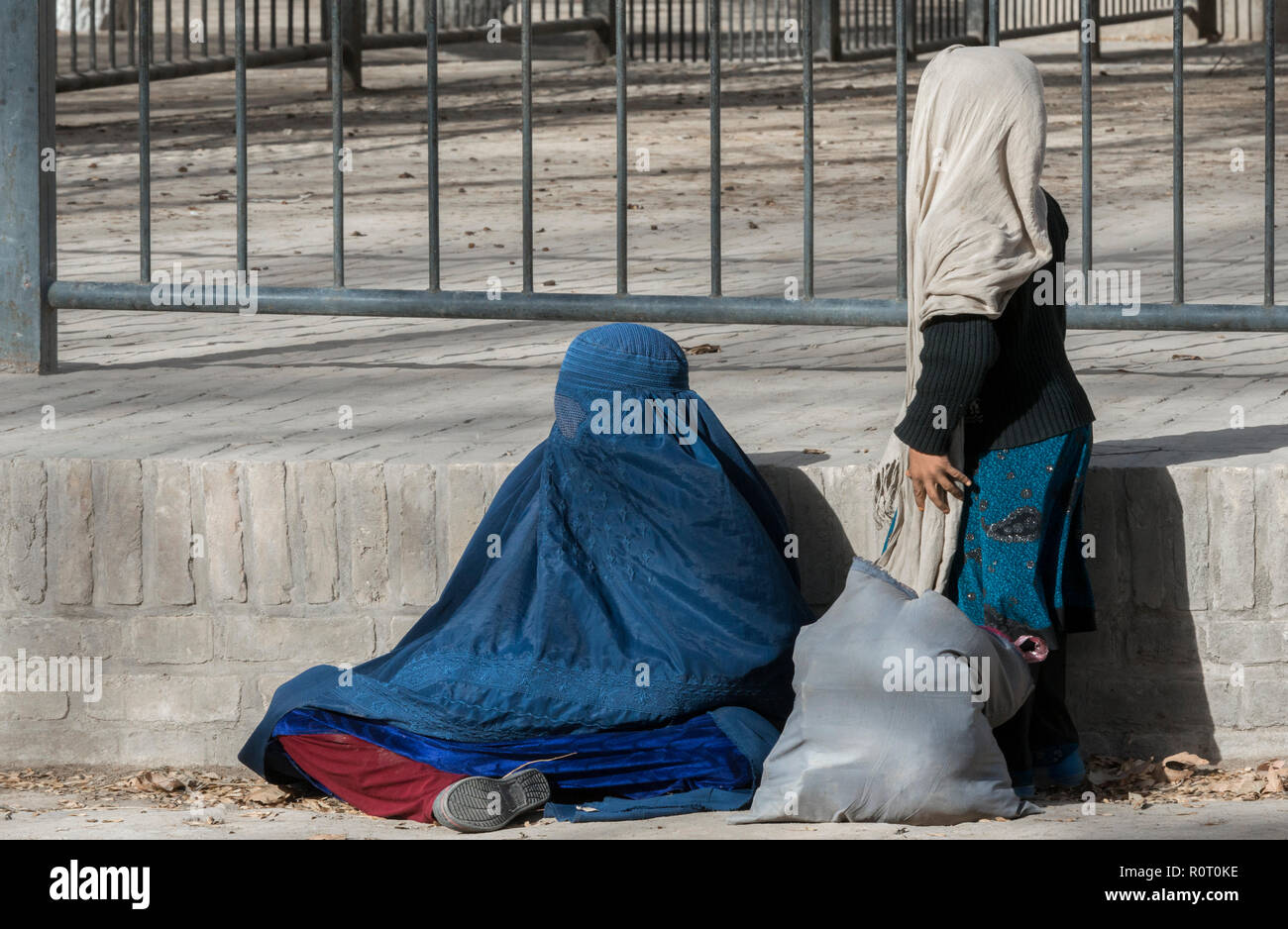 Mother Wearing Traditional Blue Burqa Sitting On The Ground In A Park ...