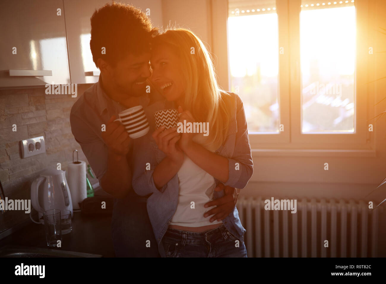Beautiful romantic couple hugging and drinking coffee in kitchen Stock ...