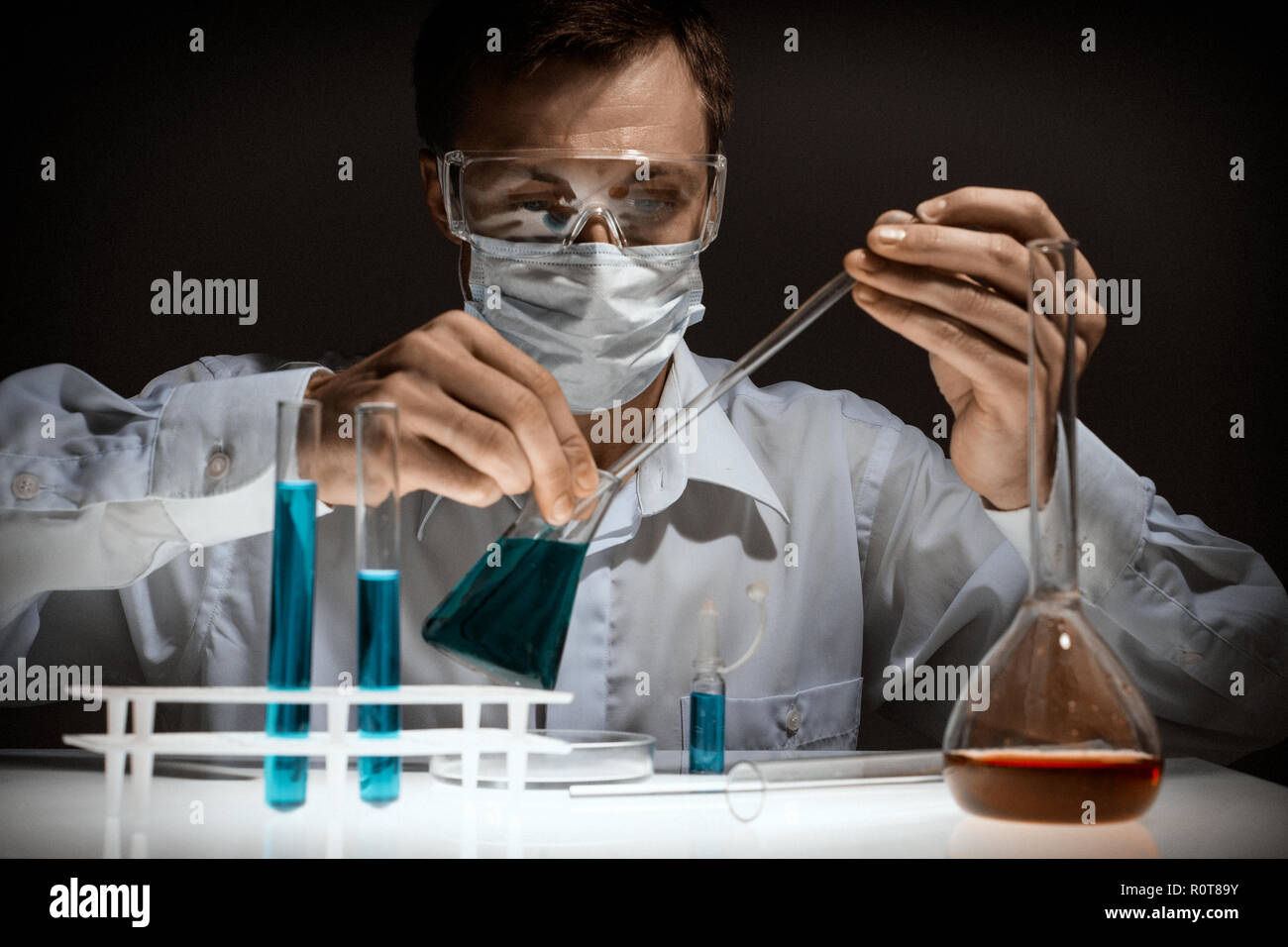 Young man scientist using auto-pipette with flask in medical science ...