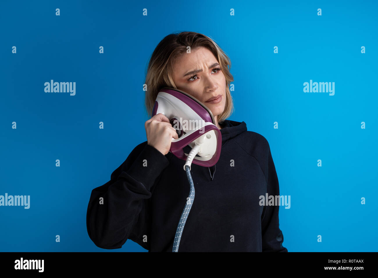 Portrait of girl pretending to talk on the phone using a flatiron ...