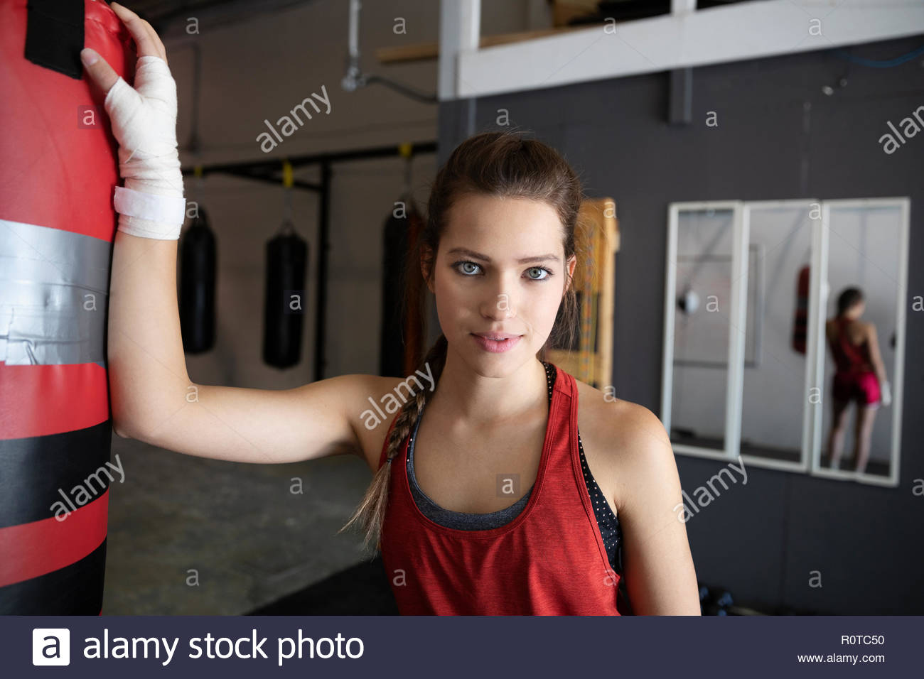 Portrait confident, tough female boxer at punching bag in gym Stock ...