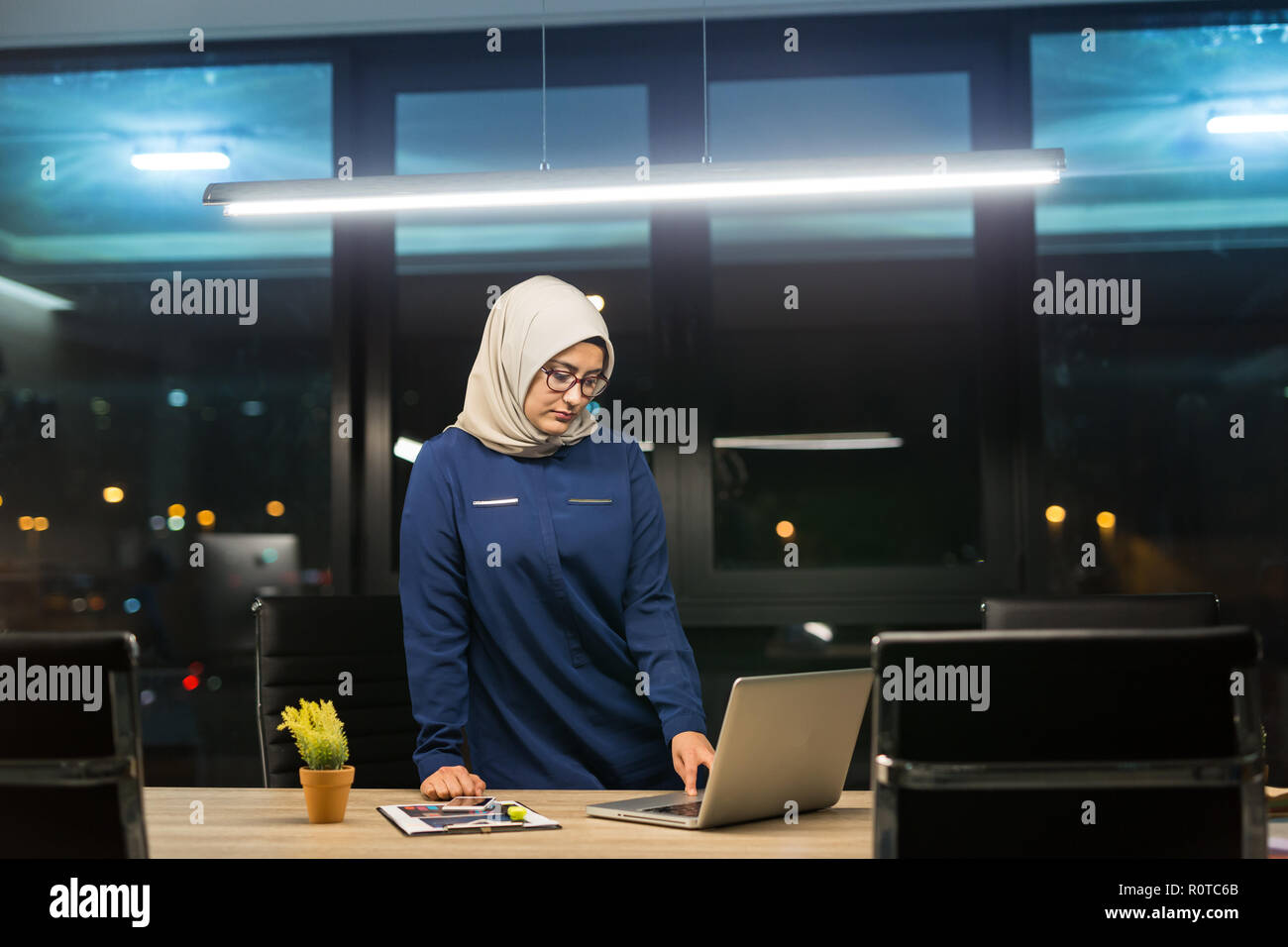 Pretty business woman working alone in dark office Stock Photo - Alamy