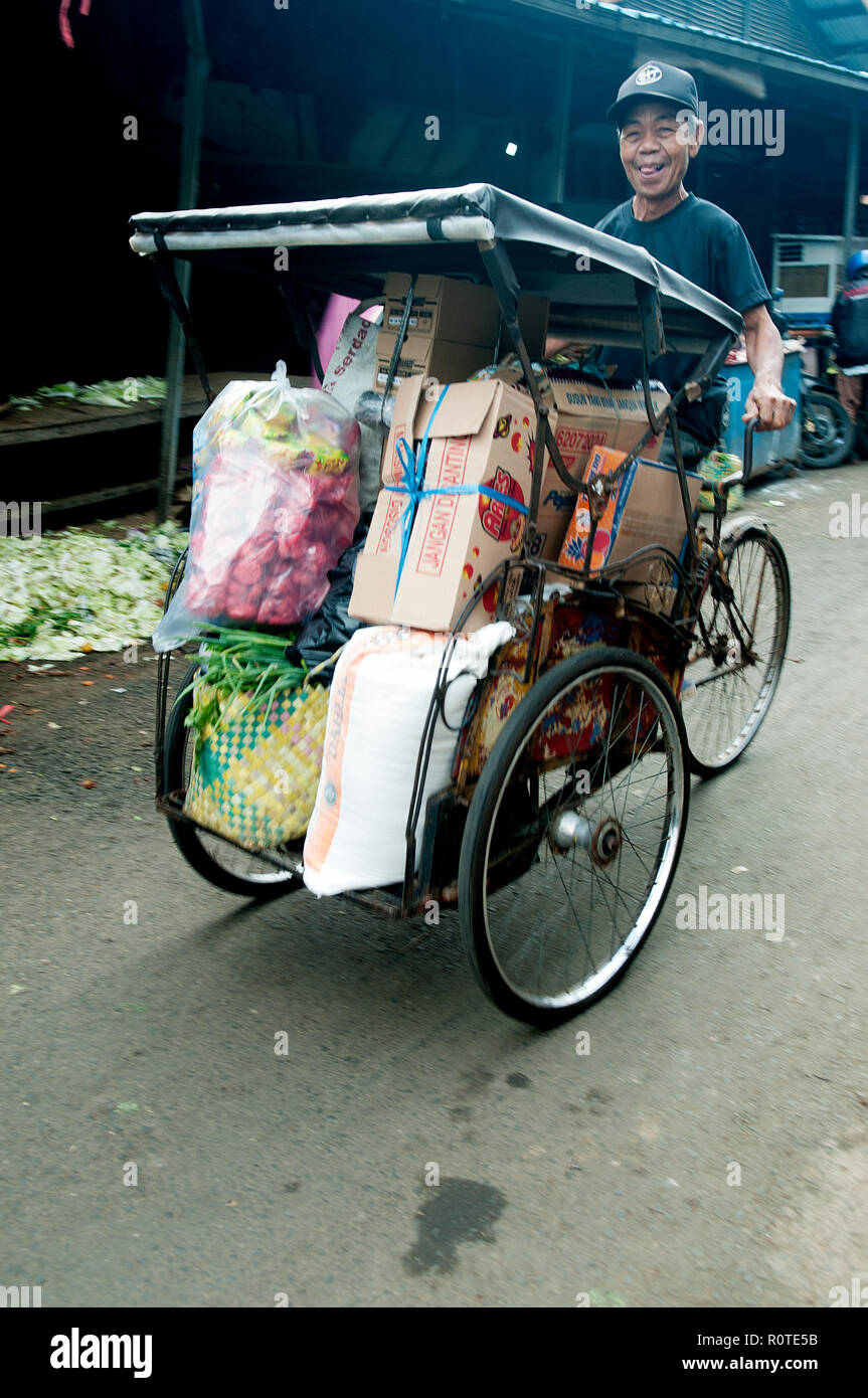 a man riding a rickshaw transporting goods in the market at Tasikmalaya ...