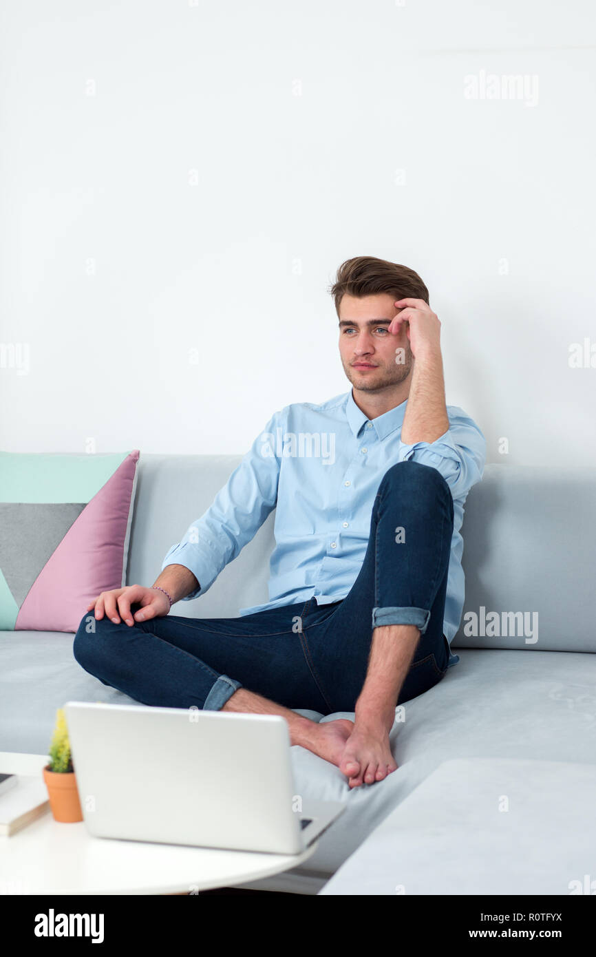 Young attractive smiling guy is browsing at his laptop Stock Photo - Alamy