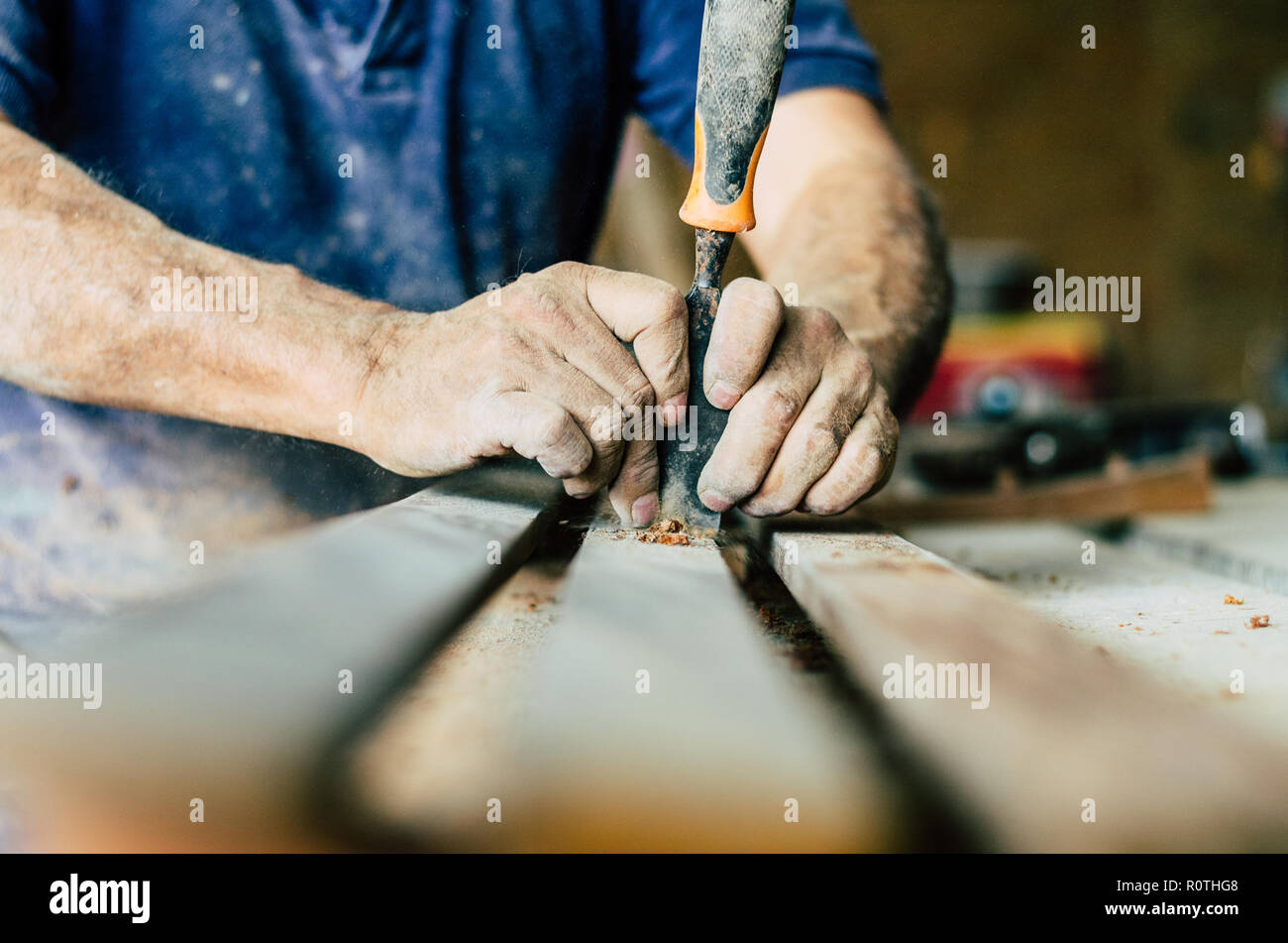 Carpenter at work, he is carving wood using a woodworking tool, hands ...