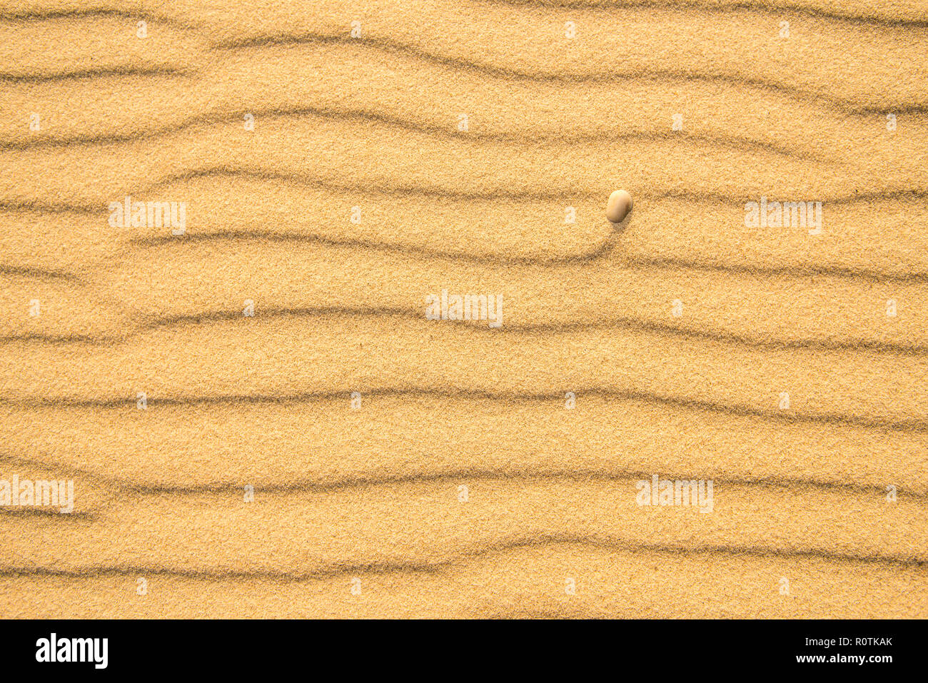 Sand of a beach with pebble and wave patterns Stock Photo - Alamy